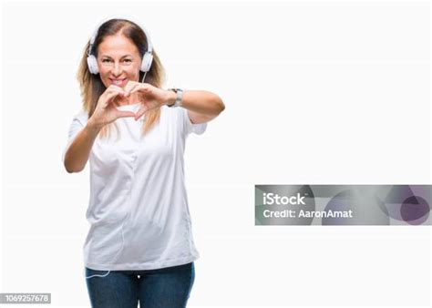중세 스페인 여자 마음 기호와 손으로 모양을 보여주는 사랑에 웃 고 고립 된 배경 위에 헤드폰을 착용 하는 음악을 듣고 낭만적인 개념입니다 갈색 머리에 대한 스톡 사진 및