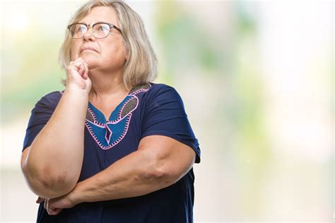 시 니 어 플러스 크기와 격리 된 배경 위에 백인 여자 입고 안경에 손을 턱 질문 잠겨있는 표현에 대 한 생각 사려깊은 얼굴 미소 의심 개념입니다 과체중에 대한 스톡 사진