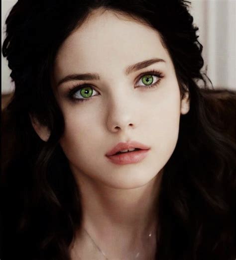 A Woman With Green Eyes Is Posing For The Camera And Has Long Dark Hair On Her Head