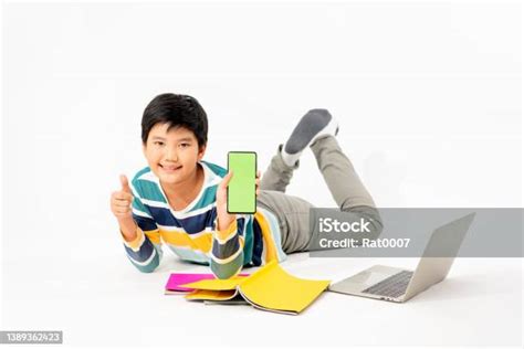 복사 공간 교육 및 기술 개념으로 흰색 배경에 고립 된 노트북과 책으로 바닥에 녹색 화면으로 휴대 전화를 들고 행복한 아시아 소년의 초상화 개발에 대한 스톡 사진 및 기타