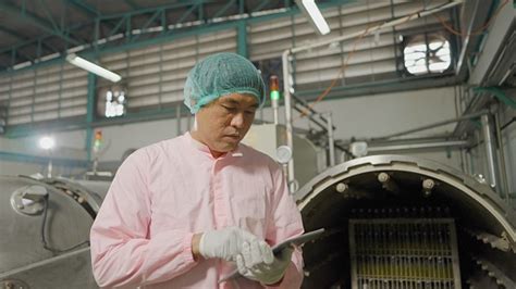 전문 식품 과학자 노동자 또는 영양사 또는 품질 관리 책임자의 초상화 헤어넷과 멸균 의류를 착용하고 제품의 품질을 확인하고 태블릿에서 기계 작업 엔지니어 또는 기술자는 라인