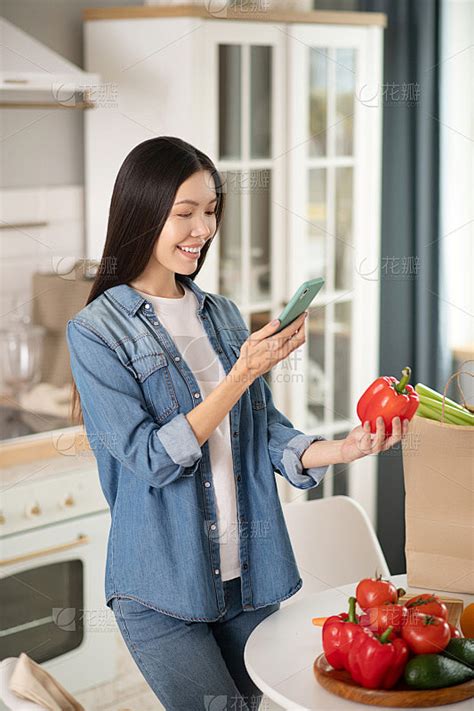 拿着智能手机和红辣椒的年轻女孩。