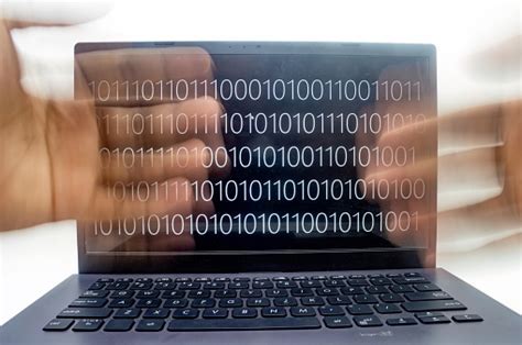 바이너리 코드로 가득 찬 노트북 화면을 향해 손을 뻗는 클로즈업은 인간과 기술의 상호 작용을 상징합니다 기술 프로그래밍 또는 데이터 개념에 적합 그래픽 사용자 인터페이스에