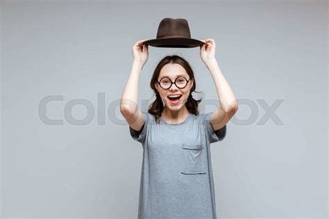 Laughing Female Nerd In Eyeglasses Holding Overhead Her Hat Colourbox