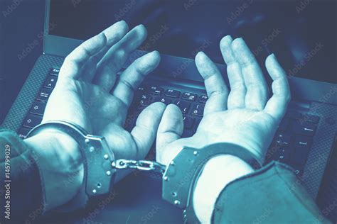 Blue Matt Toning Image Of Arrested Hacker With Hands In Handcuffs On The Laptop Keyboard Cyber
