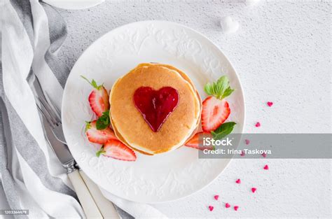 신선한 딸기와 민트가 밝은 배경의 흰색 접시위에 잼의 심장이 있는 팬케이크 더미 발렌타인 데이 아침 식사 수평 방향 공간을 복사합니다 맨 위 보기 팬케이크에 대한 스톡 사진