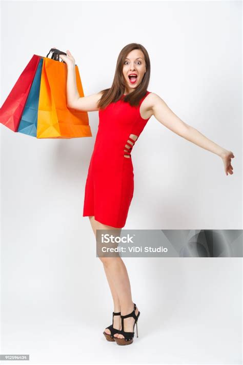 빨간 드레스 들고 멀티에서 백인 젊은 갈색 머리 여자 색 흰색 배경에 고립 된 쇼핑 후 구입 패킷을 매력적인 매력의 전체 길이입니다 광고에 대 한 공간을 복사 합니다 가방에