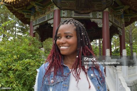희귀 한 루비 레드 염색과 아프리카 꼰 헤어 스타일을 가진 아름다운 컬러 모델의 초상화 배경에 일본 정원입니다 땋은 머리에 대한 스톡 사진 및 기타 이미지 Istock