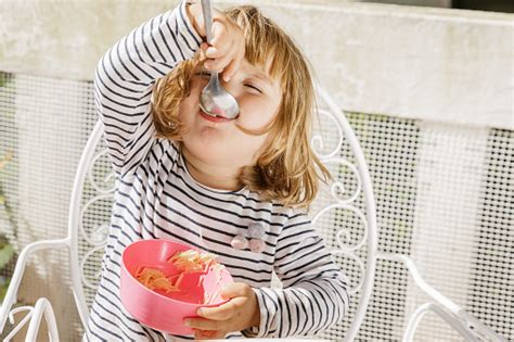테라스에서 분홍색 그릇에서 식사를하고 눈을 감은 아침 식사 중에 미소 테이블에 앉아 사랑스러운 어린 아이 가정 생활에 대한 스톡 사진 및 기타 이미지 Istock