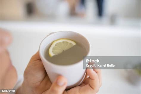 레몬 슬라이스를 곁들인 레몬 차 한 잔을 부드럽게 불고 있는 여성 감귤류 과일에 대한 스톡 사진 및 기타 이미지 감귤류 과일 건강관리와 의술 건강한 생활방식 Istock