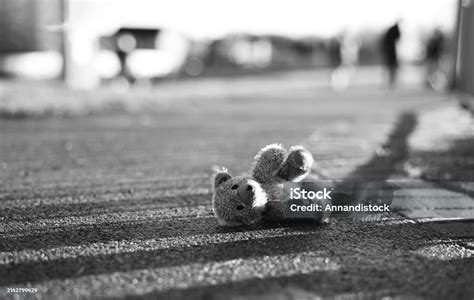 흐릿한 사람들과 함께 보도에 누워있는 슬픈 얼굴을 가진 테디 베어 이미지 블랙 화이트 우울한 날에 길에 누워있는 외로운 곰 인형 잃어버린 장난감 외로움 개념 국제 실종 아동