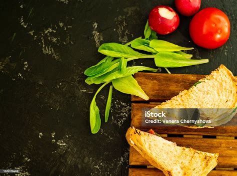 토마토와 햄을 곁들인 홈메이드 핫 샌드위치 튀긴 빵 빨간 토마토 녹색 샐러드 소시지의 맛있는 아침 식사 음식은 나무 판에 놓여