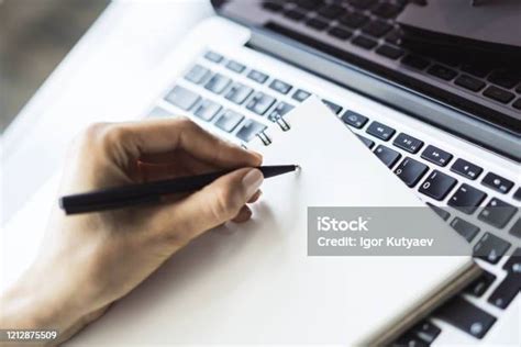 여자는 햇볕이 잘 드는 사무실 비즈니스 및 교육 개념에서 노트북 키보드에 일기에 펜으로 씁니다 클로즈업 쓰기에 대한 스톡 사진