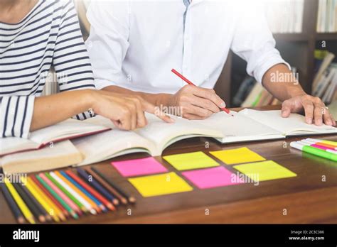 Young Students Classmates Help Friend Catching Up Workbook And Learning Tutoring In A Library