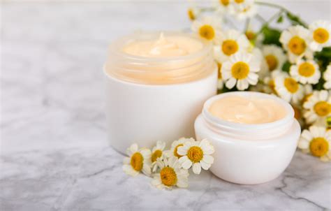 밝은 배경에 카모마일 꽃이 있는 얼굴 몸 손을 위한 보습 크림 병을 엽니다 한방 피부과 화장품 위생 크림 천연 화장품 아름다움 개념입니다 모형 0명에 대한 스톡 사진 및