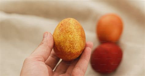 소박한 린넨 천 배경에 현대 부활절 달걀을 들고 있는 손 행복한 부활절 천연 손으로 회색 직물에 빨간색과 노란색으로 염색 계란을 만들었습니다 미의 사진