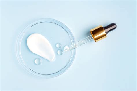 크림 스트로크와 둥근 투명한 젤 세럼 방울을 파란색 배경의 페트리 접시에 묻 힙니다 개념 실험실 테스트 및 연구 화장품 제작 및 테스트 유제에 대한 스톡 사진 및 기타