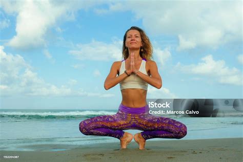 웰빙과 하모니에서 푸른 하늘 아래 휴식과 명상 운동을 하 고 아름 다운 해변에서 요가 로터스 자세와 나 마스 테 손 위치에 젊은 매력적이 고 운동 여성 가냘픈에 대한 스톡