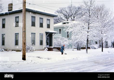 Elderly Woman Shoveling Snow Outside Her House In Winter Ca 1976 Stock