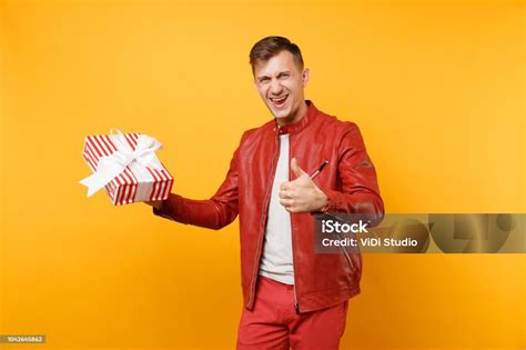 세로 보 그 웃는 잘생긴 젊은 남자 빨간 자 켓에 T셔츠 선물 밝은 동향 노란색 배경에 고립 된 선물 상자를 개최 사람들이 진심으 감정 라이프 스타일 개념 광고 영역입니다