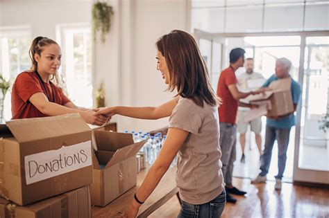 자원봉사자들이 패키지를 분류하는 기부 센터에서 음식과 옷을 든 상자를 기부하는 여성 자선기부에 대한 스톡 사진 및 기타 이미지 자선기부 기부함 상자 Istock