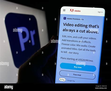 Person Holding Cellphone With Webpage Of Video Editing Software Adobe Premiere Pro On Screen In