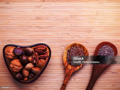 오메가 3와 불포화 지방의 엄선 식품 공급원 슈퍼 푸드 높은 비타민 E와식이 섬유는 건강 식품을위한 아몬드 피칸 헤이즐넛 호두 아마씨 및 치아씨를 대나무 도마에 넣습니다