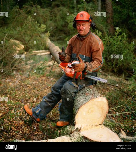 Mid Adult Man Sitting On Chopped Tree Trunk With Chainsaw Portrait Stock Photo Alamy