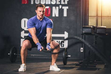 크로스 핏 체육관에서 전투 로프 운동을하는 백인 운동 선수 체육관에서 운동하는 동안 크로스 핏 운동을하는 집중 된 남자 스포츠웨어 훈련 운동에 집중 된 남자 근력 운동 35