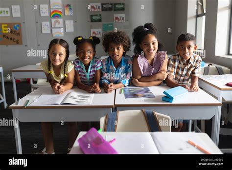 Smiling Multiracial Elementary School Students Sitting At Desk In