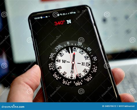 Hand Holding Smart Phone With Digital Compass App Shown On Its Screen