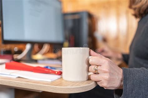 Detail Of Womans Hand Holding A Cup Of Coffee While Teleworking From
