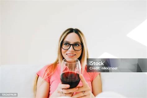 젊은 백인 쾌활한 여자는 와인을 마시고 집에서 소파에 앉아 긍정적인 감정 표현에 대한 스톡 사진 및 기타 이미지 긍정적인 감정 표현 러시아 레저 활동 Istock