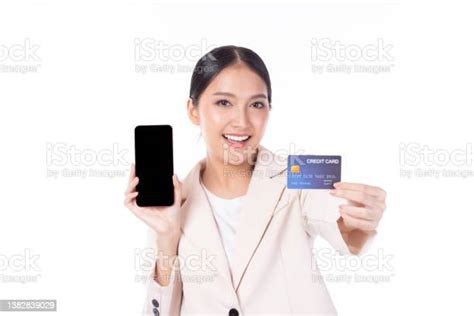초상화 아시아 행복 젊은 소녀는 분홍색 정장 행복한 미소를 입고 흰색 배경에 고립 된 휴대 전화를 들고있는 동안 플라스틱 신용 카드를 보여줍니다 비즈니스 온라인 쇼핑 개념