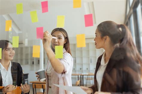 Asian Businesswoman Teamwork Planning With Sticky Notes And New Ideas On A Glass Wall Stock
