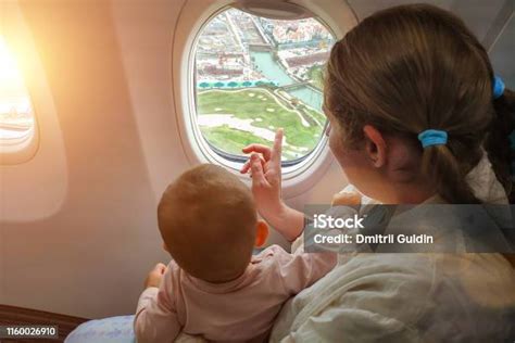 어린 아이를 가진 엄마는 비행기의 창문을 내다보며 땅에 떨어졌다 1년 미만의 유아 소녀와 함께 여행하는 경우 2명에 대한 스톡 사진 및 기타 이미지 Istock