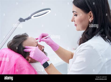 Cosmetologist Female Putting Marks On Male Patient Forehead Before Beauty Injection Stock Photo