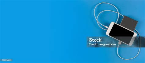 복사 공간이있는 파란색 배경에 전원 뱅크충전 상단 보기 스마트 폰 흰색 Usb 케이블로 전원 뱅크로 충전하는 스마트 폰 휴대폰 배터리 충전기에 대한 스톡 사진 및 기타