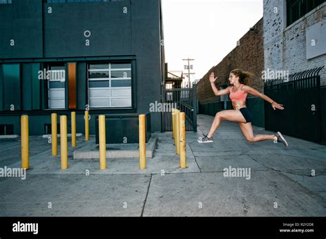 Female Athlete Running On Sidewalk Past Industrial Buildings Stock Photo Alamy