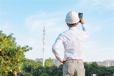 흰색 안전 헬멧을 착용한 엔지니어는 휴대 전화 신호를 연구합니다 25 29세에 대한 스톡 사진 및 기타 이미지 25 29세 Brand Name Smart Phone