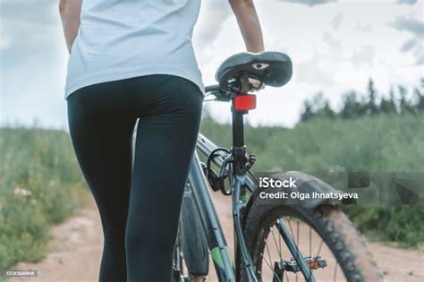흰색 셔츠를 입은 둥 글래드 금발 여성 검은 색 레깅스는 흐린 여름 날 뒤에서 사진 필드의 중간에 모래 도로에 자전거를 롤 가냘픈에 대한 스톡 사진 및 기타 이미지 Istock