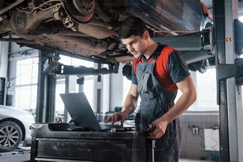 심각한 손상된 차량 작업장에서 망가진 차를 고치기 위해 노트북을 사용하는 제복을 입은 남자 사진 Unsplash의 사람 이미지