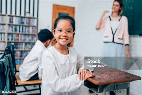 학교 교실에 자신 있게 앉아 포즈를 취하면서 카메라를 바라보며 웃고 있는 어린 아이의 초상화 4 5세에 대한 스톡 사진 및 기타 이미지 Istock