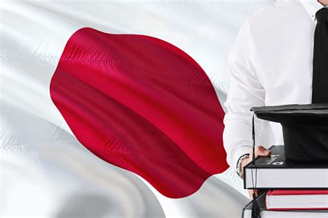 성공적인 일본 학생 교육 컨셉 일본 국기 배경 위에 책과 졸업 모자를 들고 교사 교육 관련 직업에 대한 스톡 사진 및 기타 이미지 교사 교육 관련 직업 교육 기