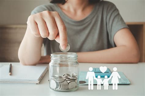 돼지 저금통에 동전을 놓고 가족 아이콘을 테이블에 올려놓는 여자 기부 저축 자선 가족 재정 계획 개념 기금 모금 연금 투자 금융 위기 개념 자선기부에 대한 스톡 사진 및