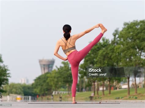 스포츠웨어 빨간 바지 야외에서 요가를 연습하는 건강 한 여성의 뒷모습 큰 발가락 포즈에 손을 뻗어 운동 우티타 하스타 파단 구스타사나에 서 공원 배경전체 길이 건강한 생활