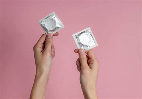 2 Hands Holding Up Condoms To Ask Can You Have Sex On Your Period And Get Pregnant