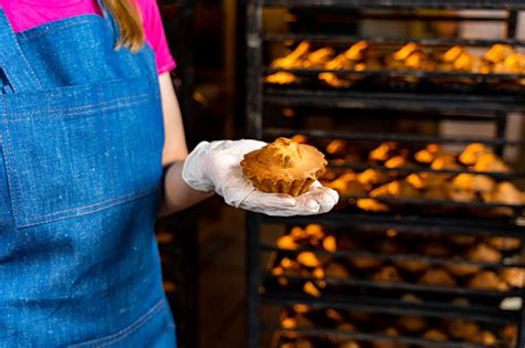 베이커리 제품의 생산 젊은 여성 베이커가 빵집에서 컵케이크를 손에 들고 있습니다 공장 산업 건물에 대한 스톡 사진 및 기타 이미지 공장 산업 건물 달콤한 롤빵 달콤한