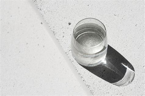 미적 햇빛 그림자가 있는 중립 콘크리트 배경에 순수한 물이 있는 유리 순수함과 단순함 장면 0명에 대한 스톡 사진 및 기타