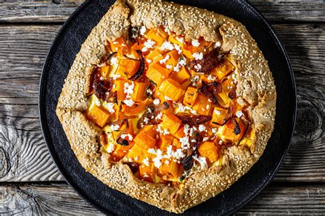 캐러멜화 양파와 부스러진 페타 치즈를 소박한 나무 테이블에 얹은 호박 갈레트 위에서 수평 평평한 평지 클로즈업 0명에 대한 스톡 사진 및 기타 이미지 Istock